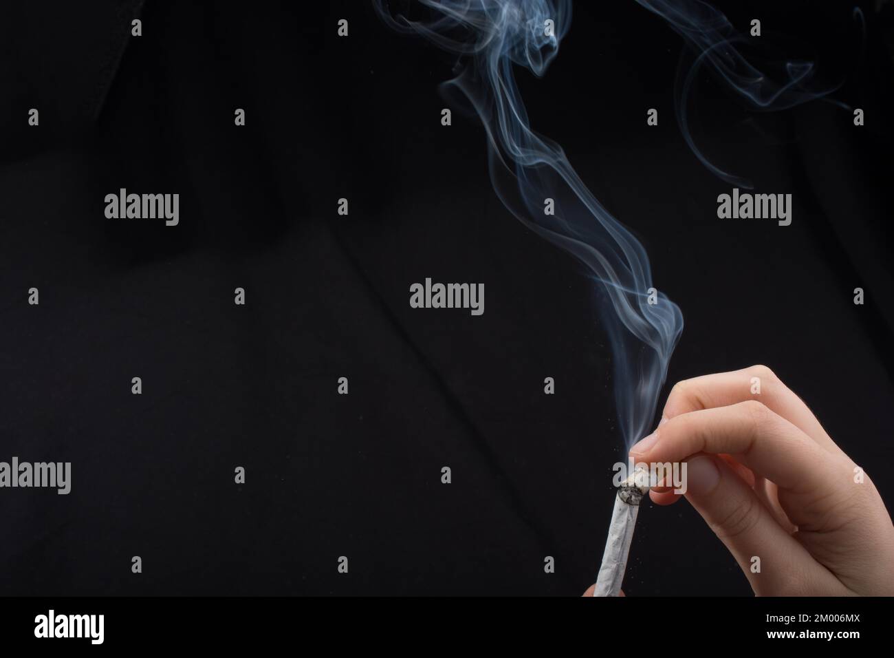 Hand is holding smoking cigarette with smoke around Stock Photo - Alamy