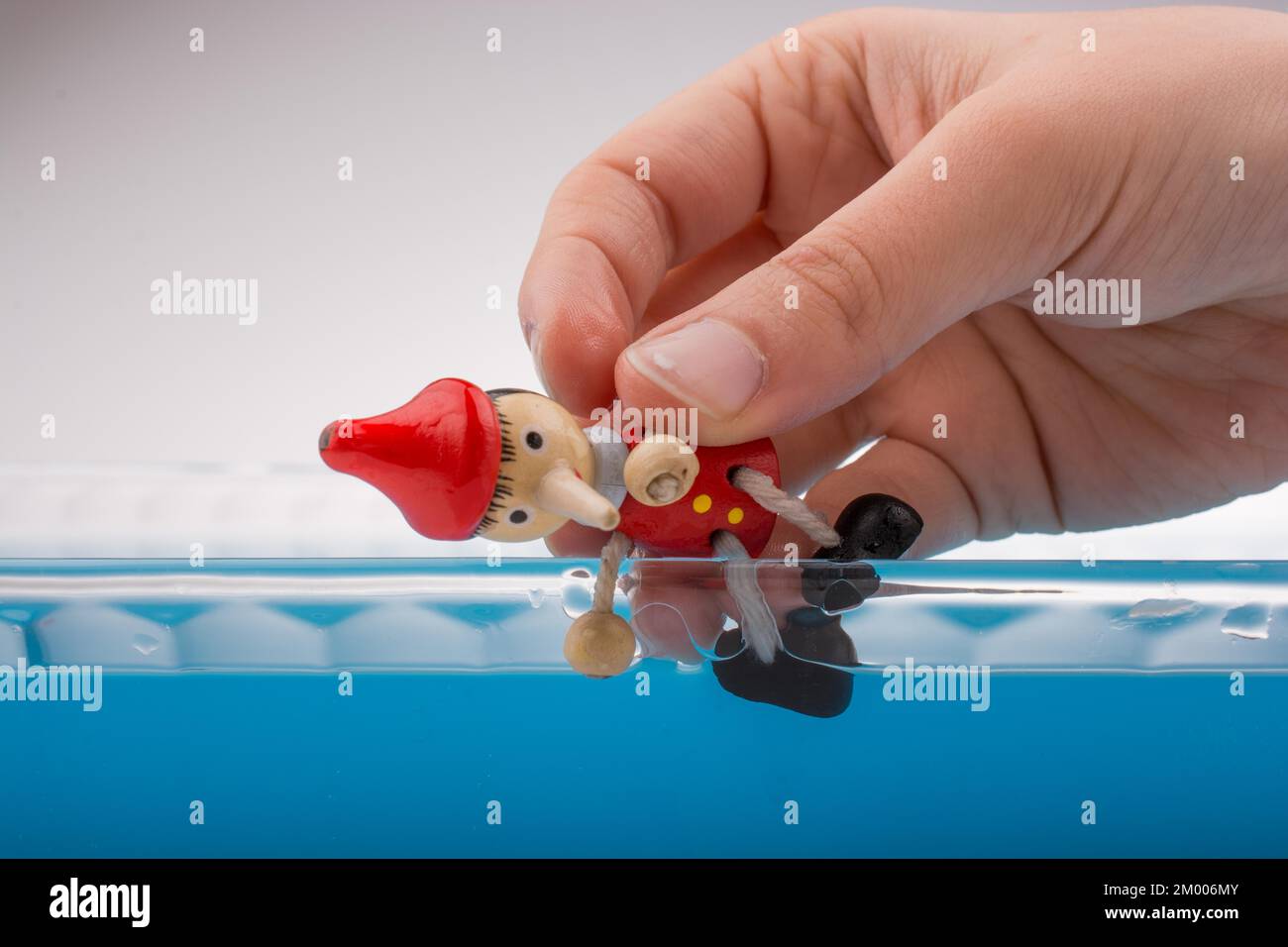 Hand holding wodden puppet Pinocchio on in blue water Stock Photo - Alamy