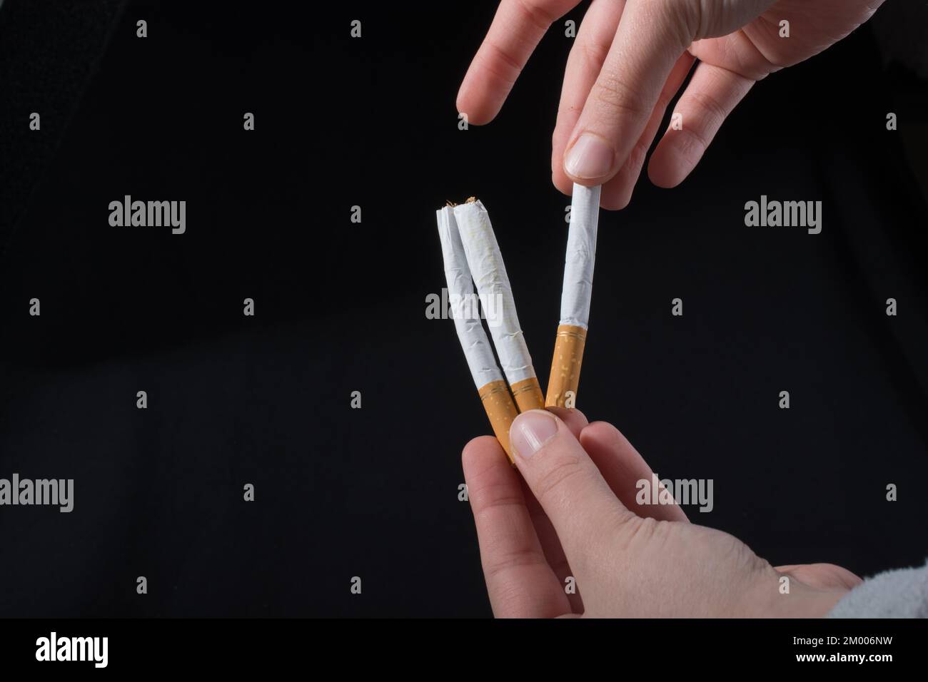 Hand is giving out cigarette on a black background Stock Photo - Alamy