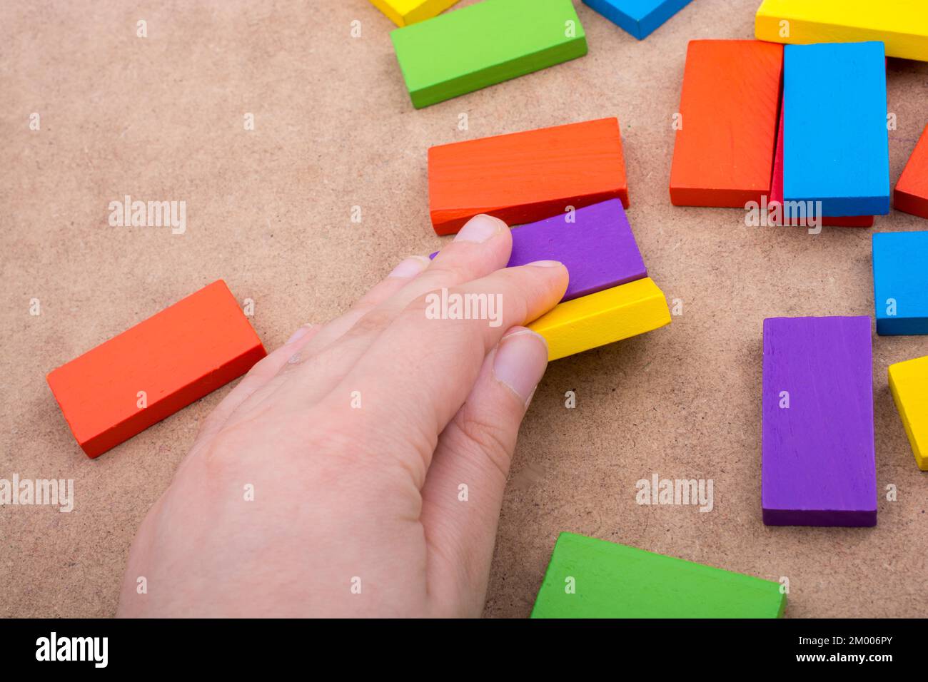 Hand holding one of the wooden blocks of various colors Stock Photo - Alamy