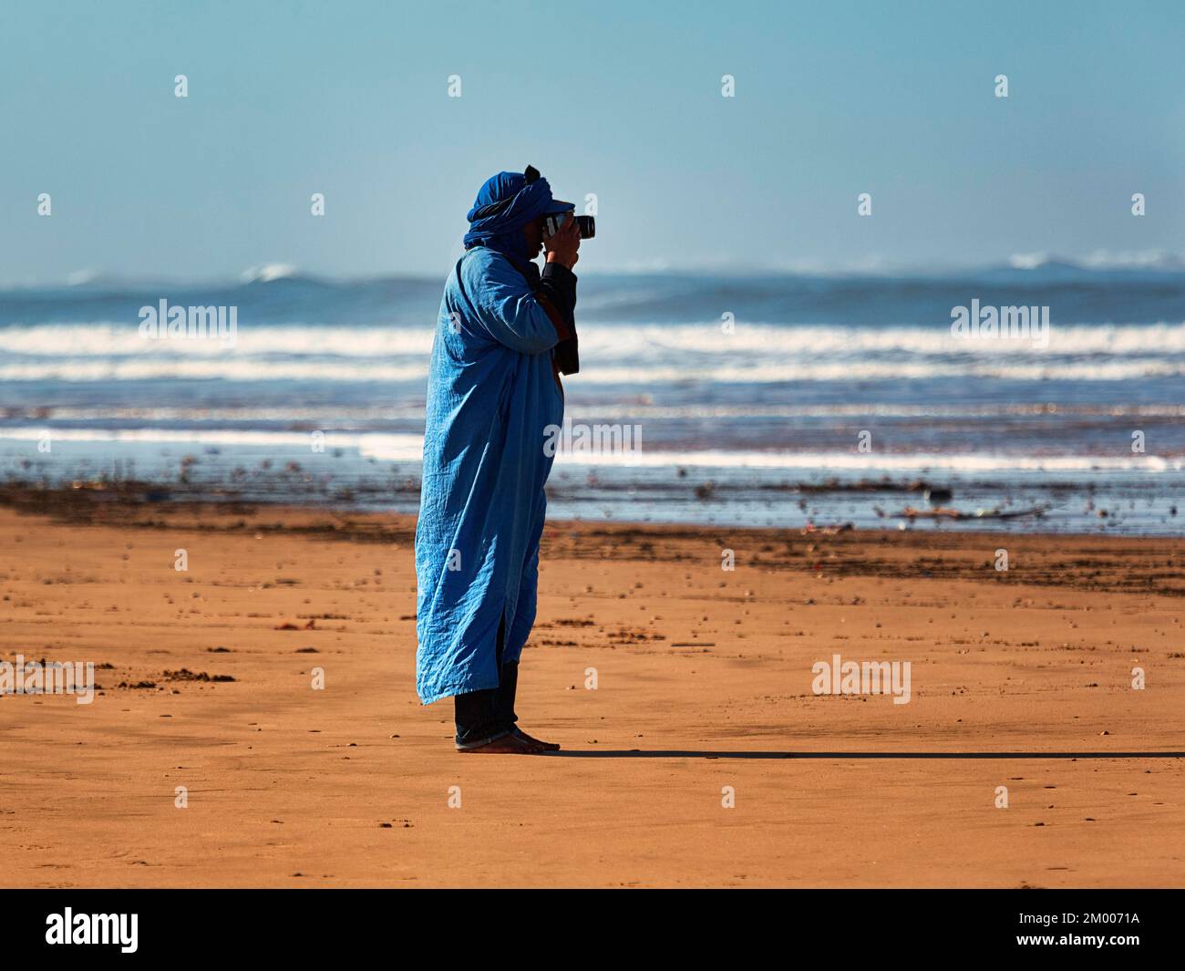 Photographer, Berber in typical blue clothing photographed on the beach ...