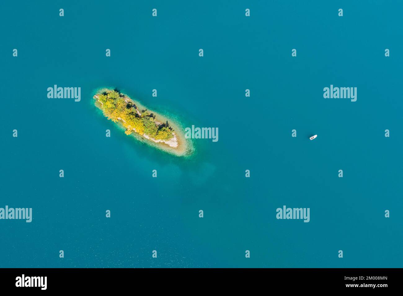 Bird's eye view of white boat and chive island in the turquoise waters ...