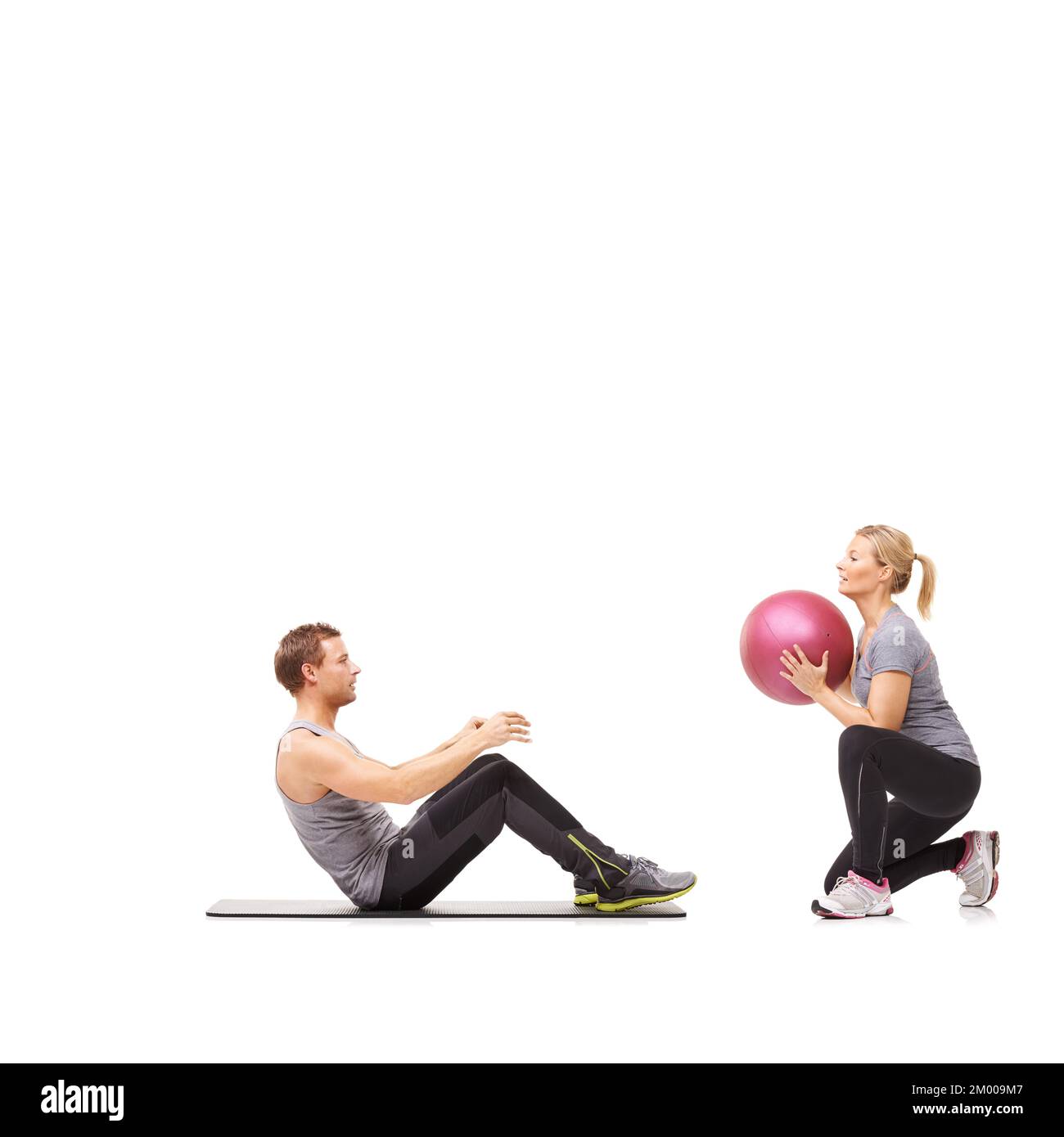 Exercise partners. A man and woman exercising their abs by passing a ...