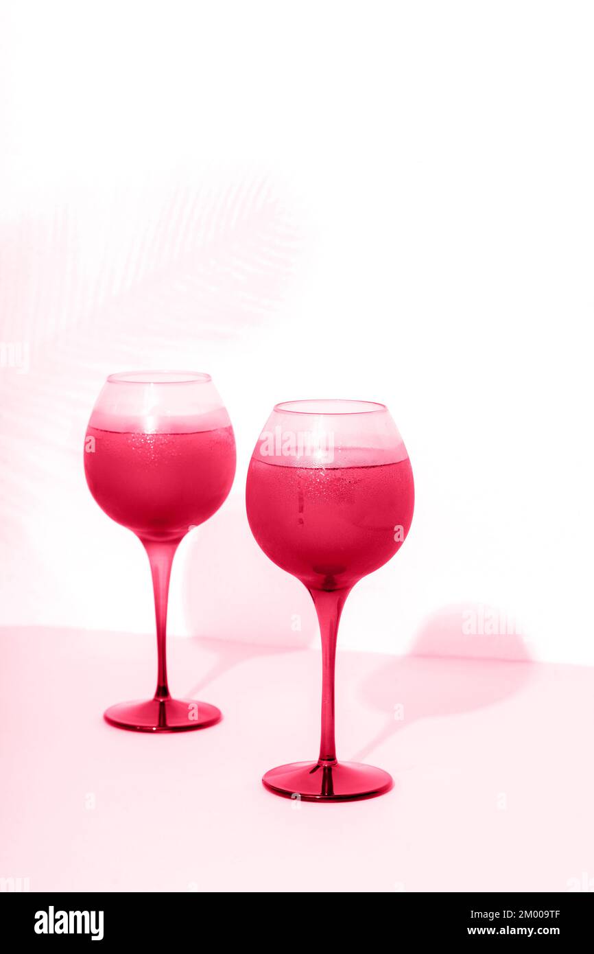 Viva magenta cocktail with ice in wineglasses on a pink table, tropical ...