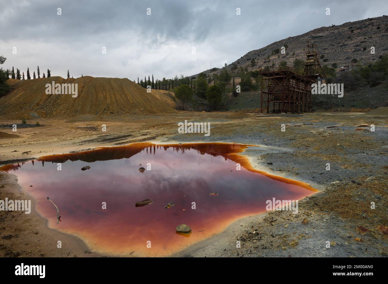 Abandoned copper mine with red toxic water and dramatic stormy cloudy ...