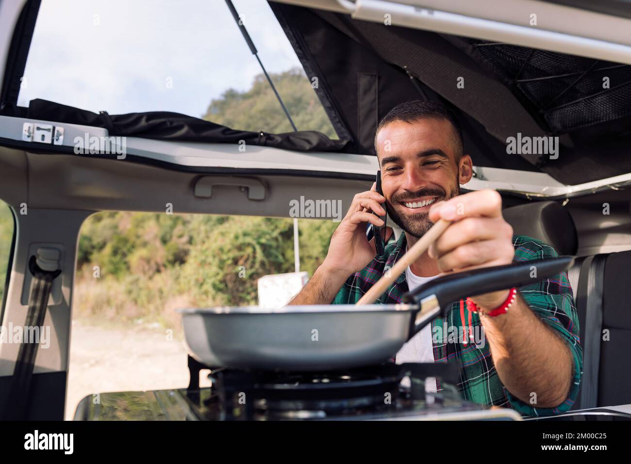 man talking on phone while cooking in his van Stock Photo - Alamy