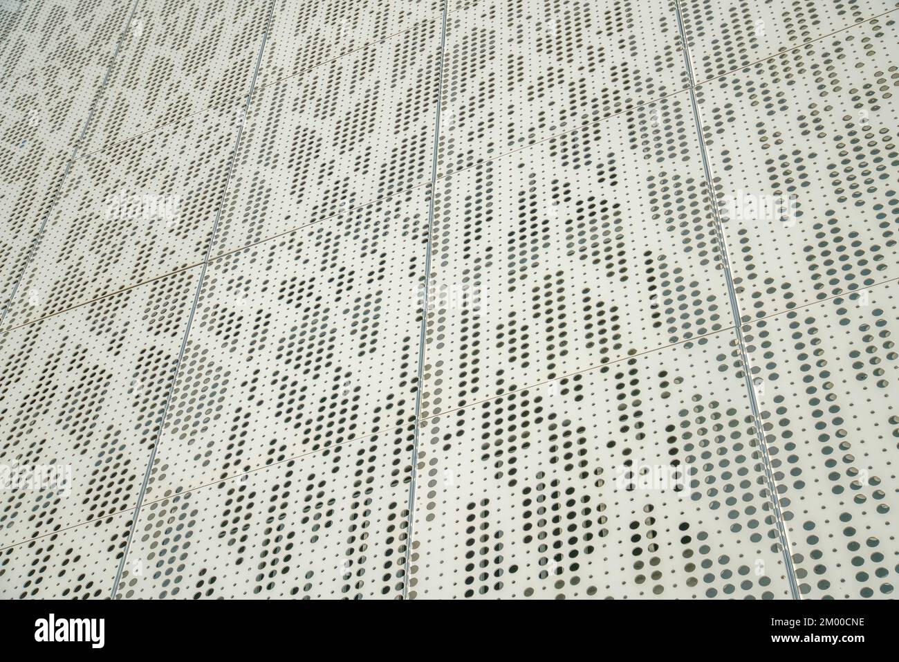 Low angle view of a beige metal wall sheet with decorative uneven holes ...