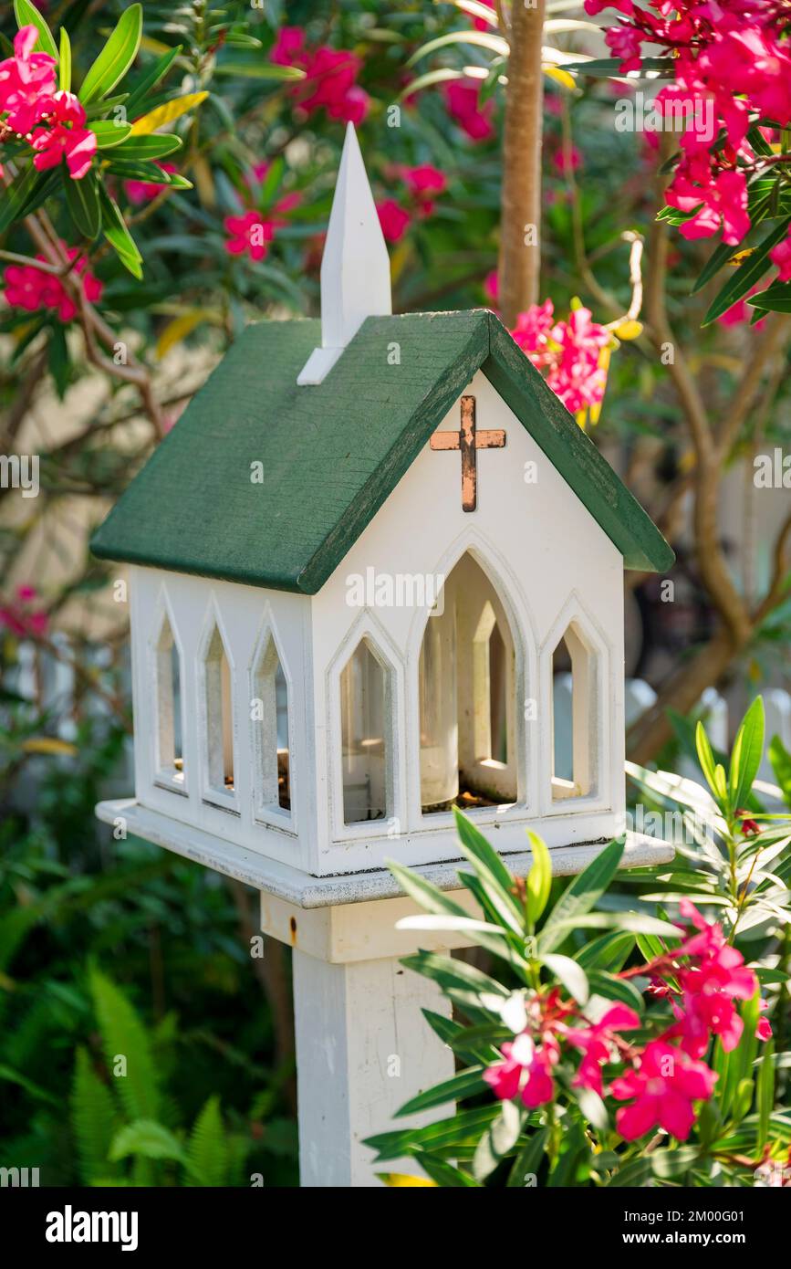 Wooden miniature church on a post with cross at the roof peak near the ...