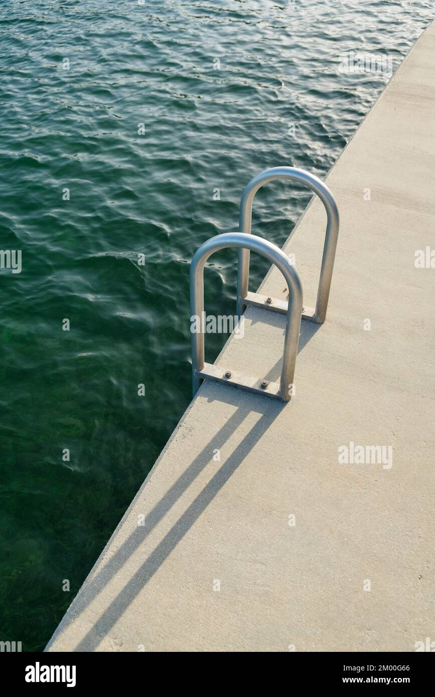 Handrails of a metal seawall ladder at the bay in Miami, Florida. There ...