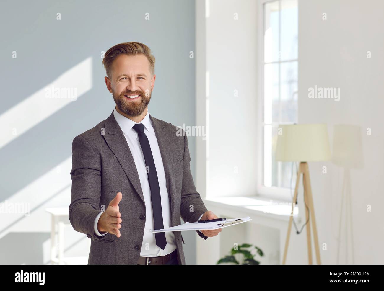 Portrait of happy real estate agent in suit smiling and offering hand ...