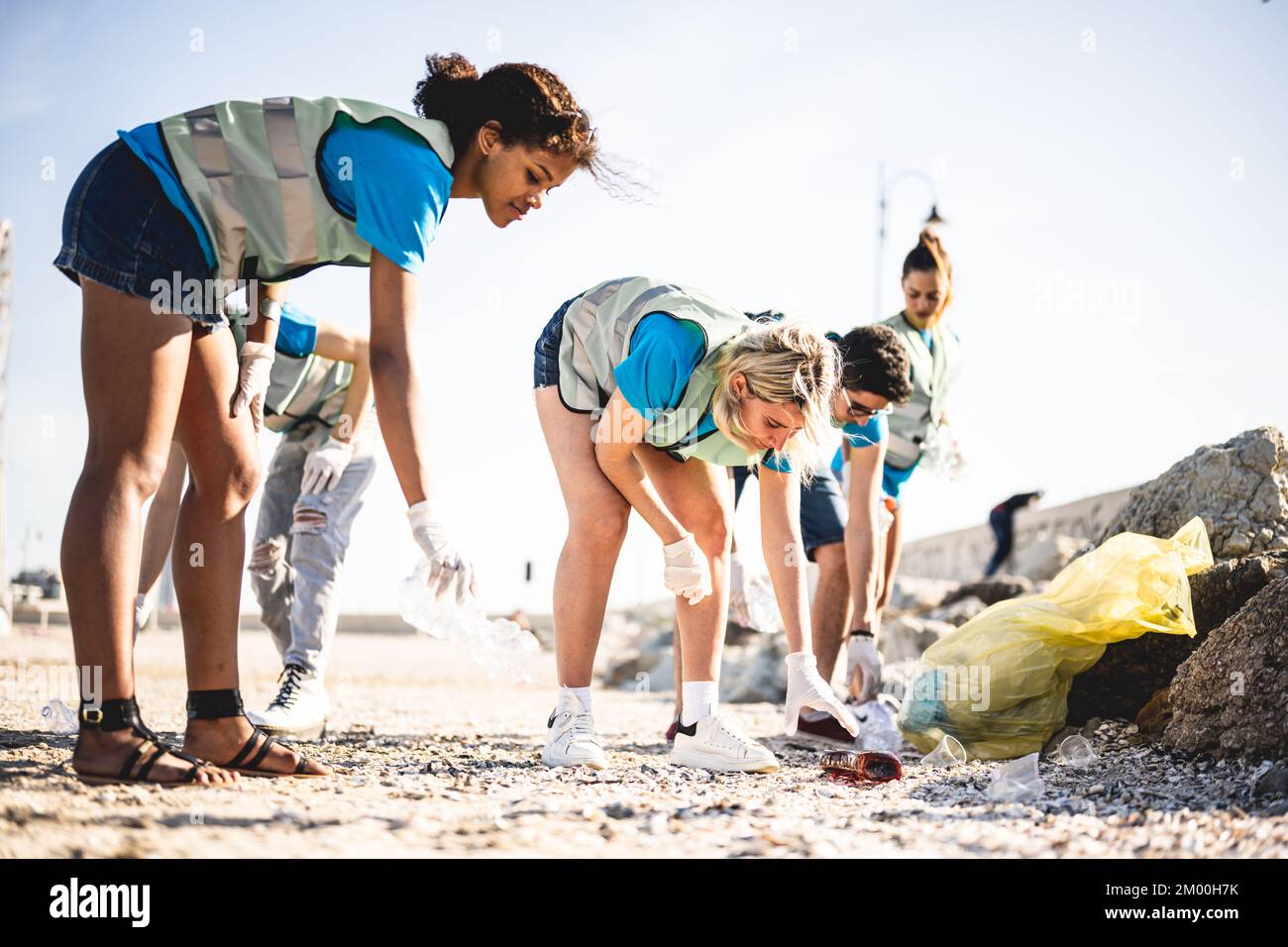 Diverse people cleaning up the beach, volunteers collecting the waste ...