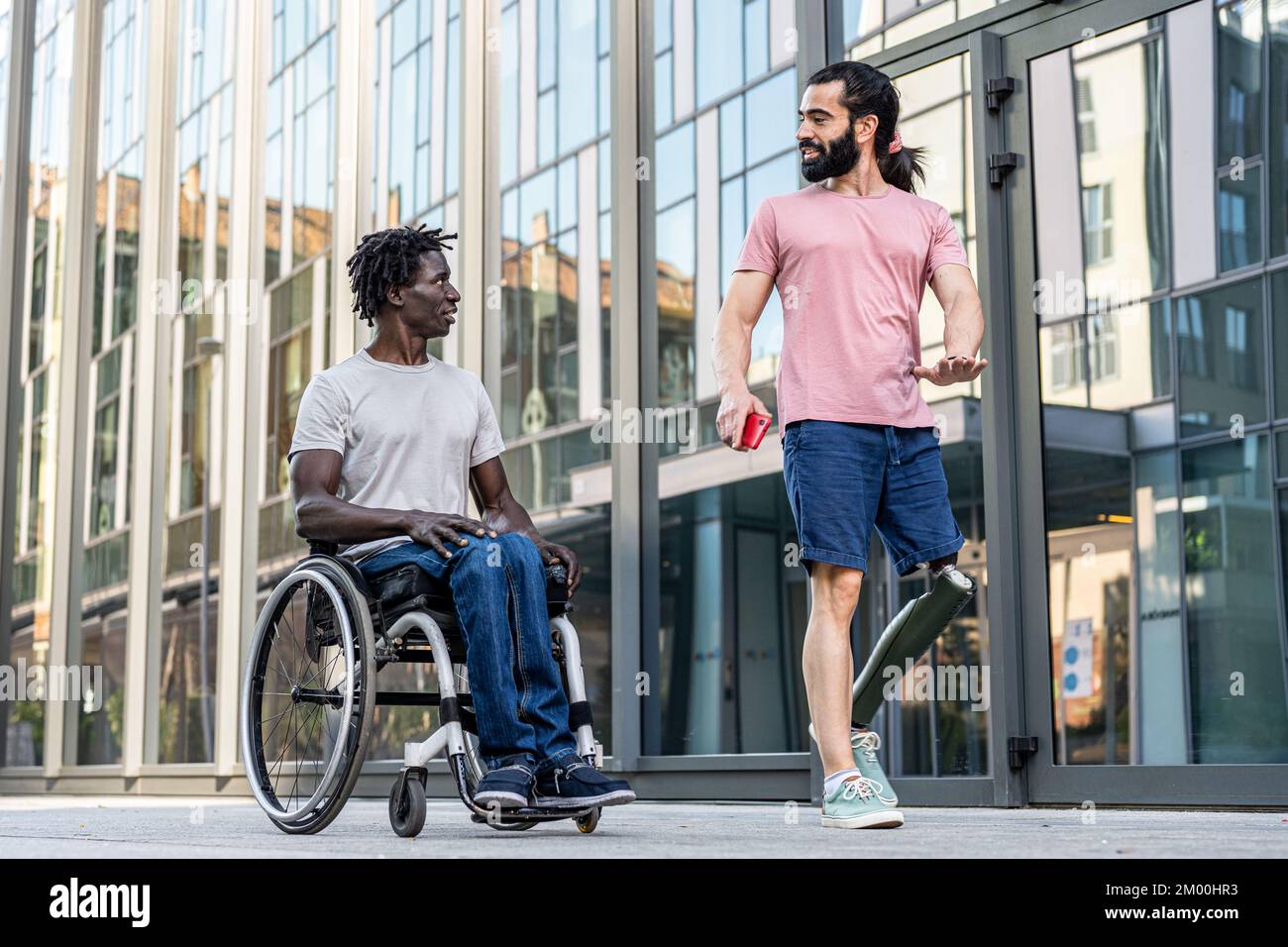 Two diverse friends having some disabilities walking in the city ...