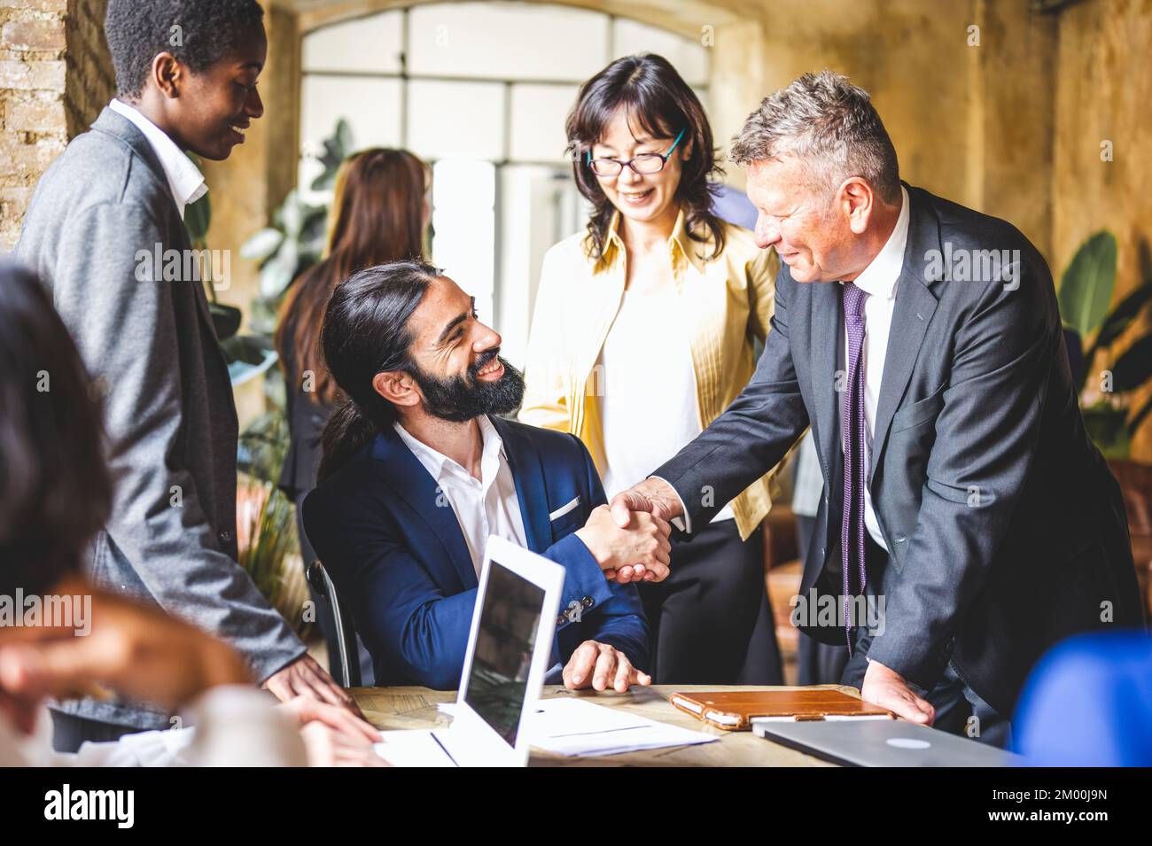 Diverse businesswomen and businessmen making a successful deal ...