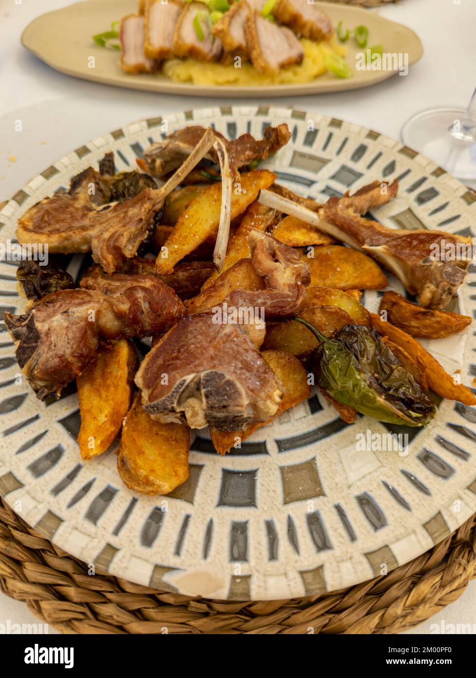 lamb chops with french fries on white plate with green chili peppers ...