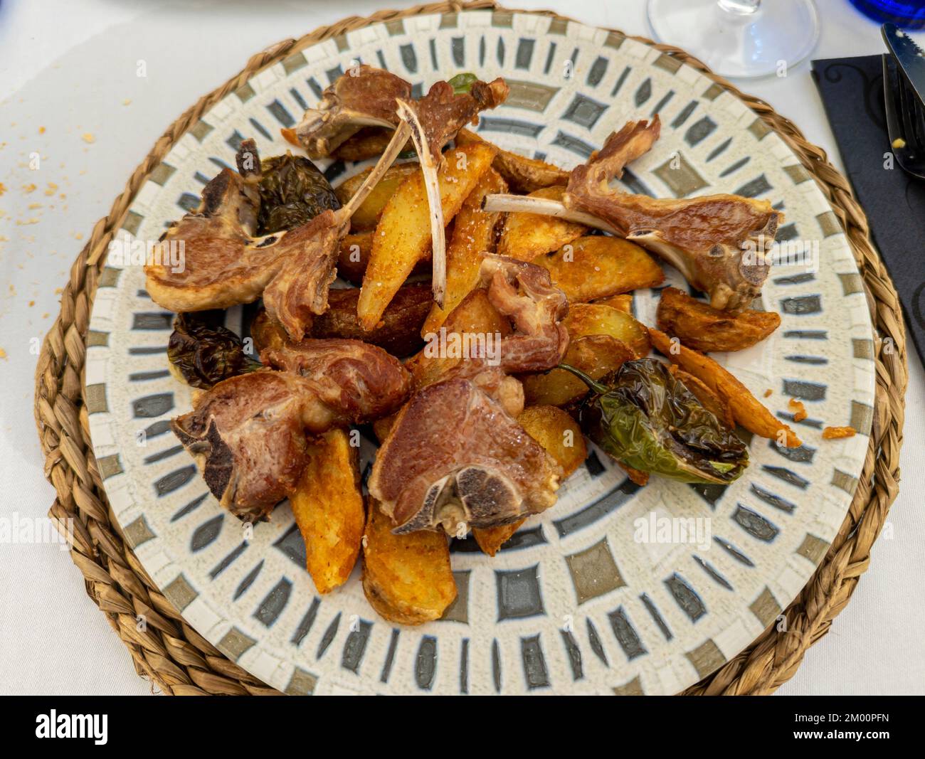 lamb chops with french fries on white plate with green chili peppers ...