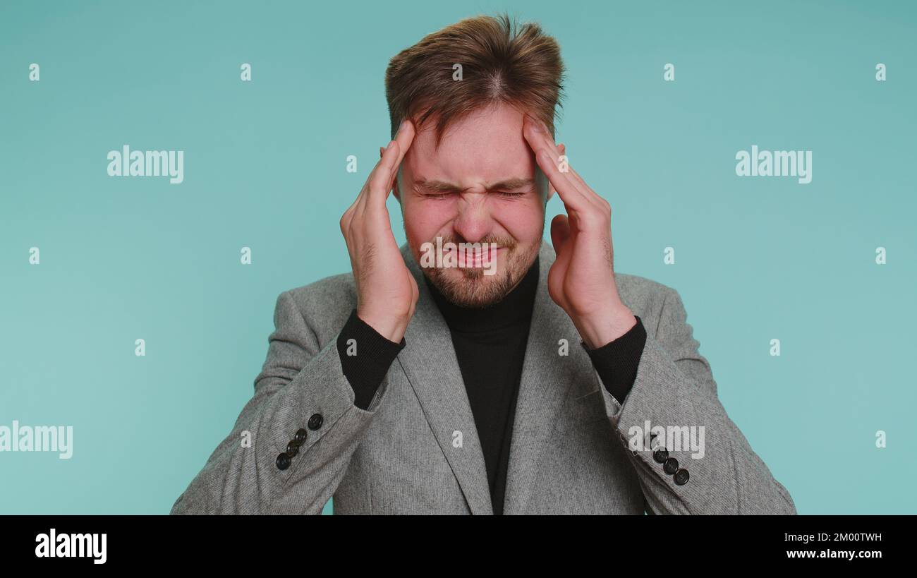 Bearded young adult business man rubbing temples to cure headache ...