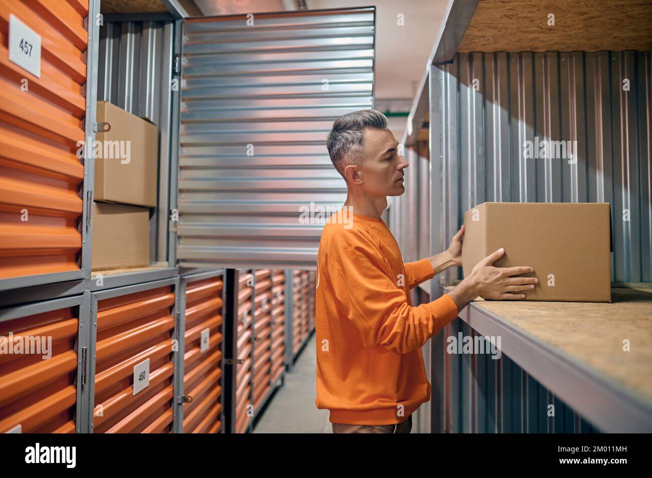 Side view of a calm focused worker putting the packaged cardboard box ...