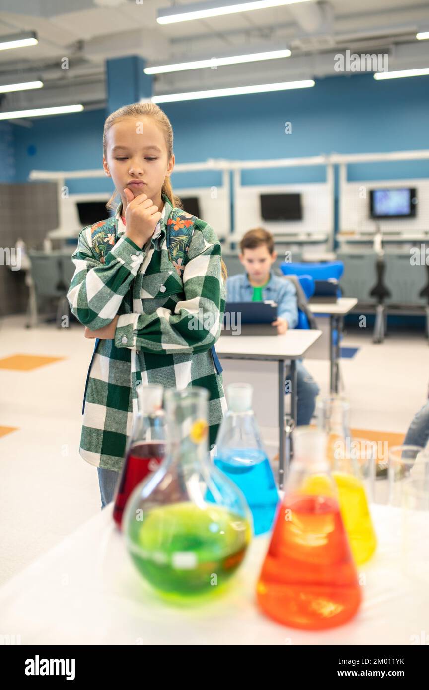 Thinking. Concentrated girl meditating attentively looking at chemical ...
