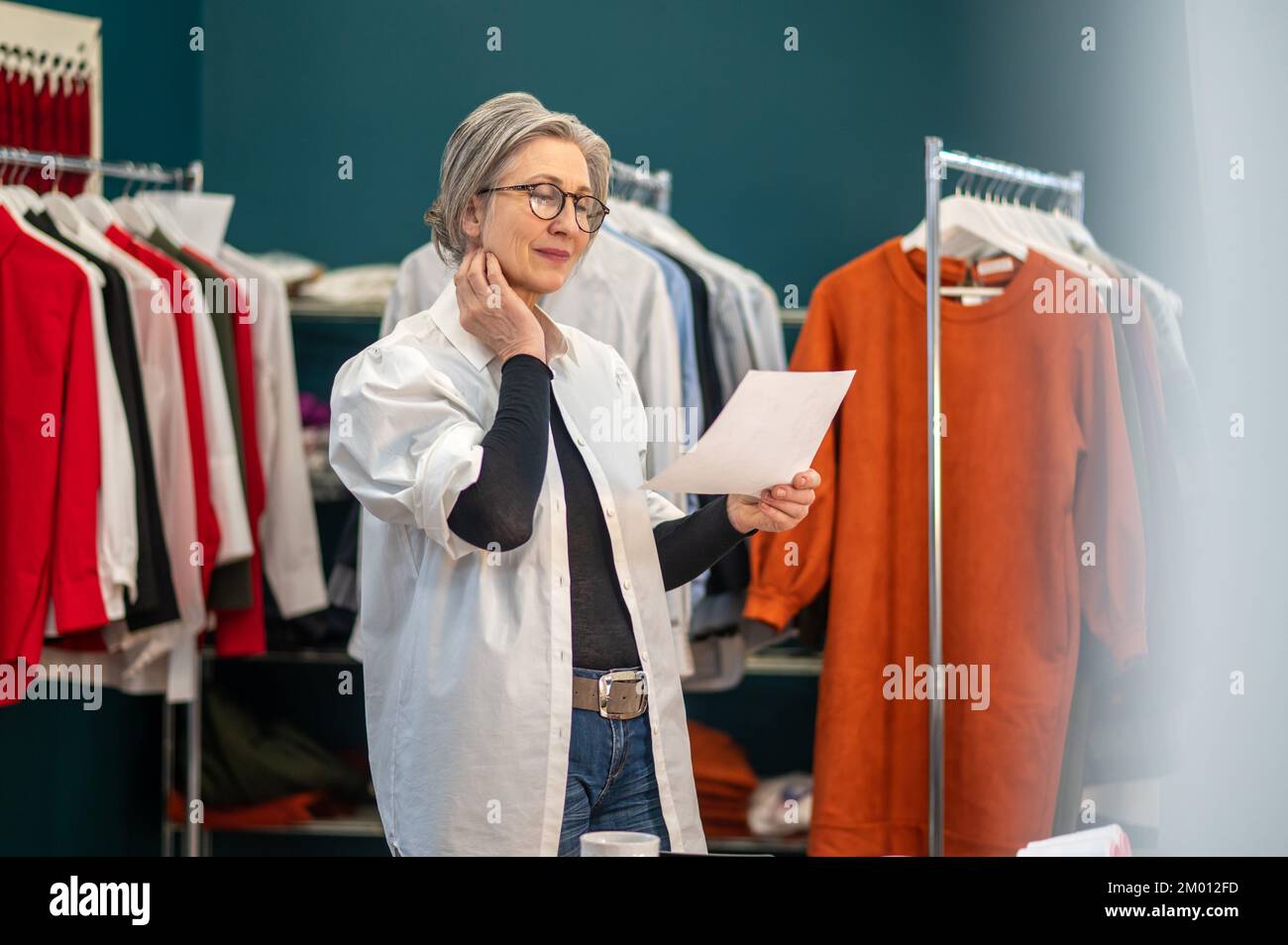 Inspiration. Smiling interested adult woman in glasses looking at piece ...