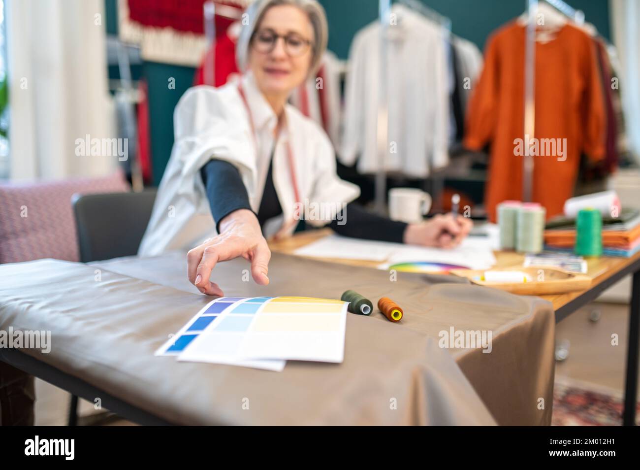 Creative process. Woman sitting at table stretching hand with color ...