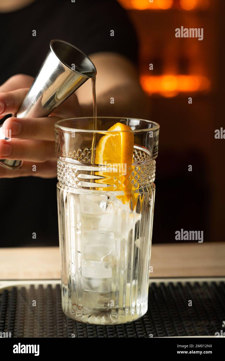 Bartender pouring a gin from the steel jigger to the glass on the bar counter. Copy space Stock ...