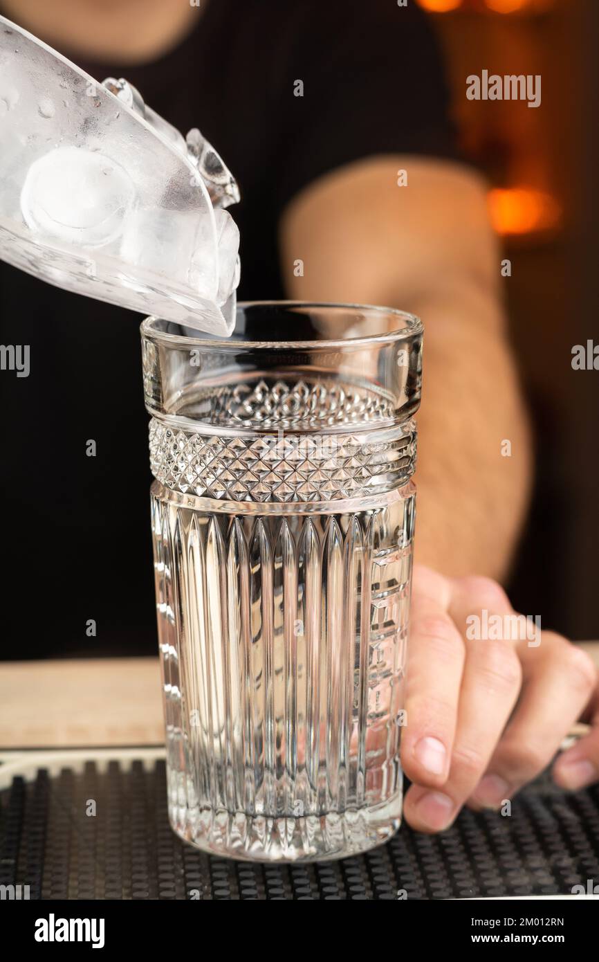 Bartender making ice cocktail with help of the bar equipment on the bar ...