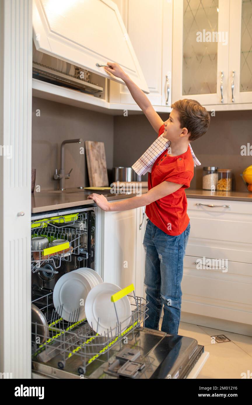 Smiling pleased Caucasian boy opening the drying rack mounted over the ...
