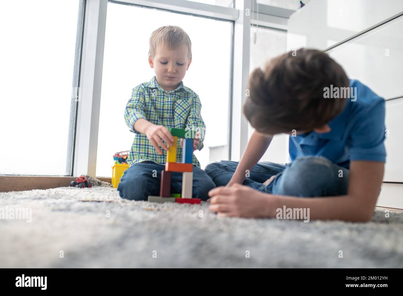 Serious concentrated cute blond male child joining together several ...