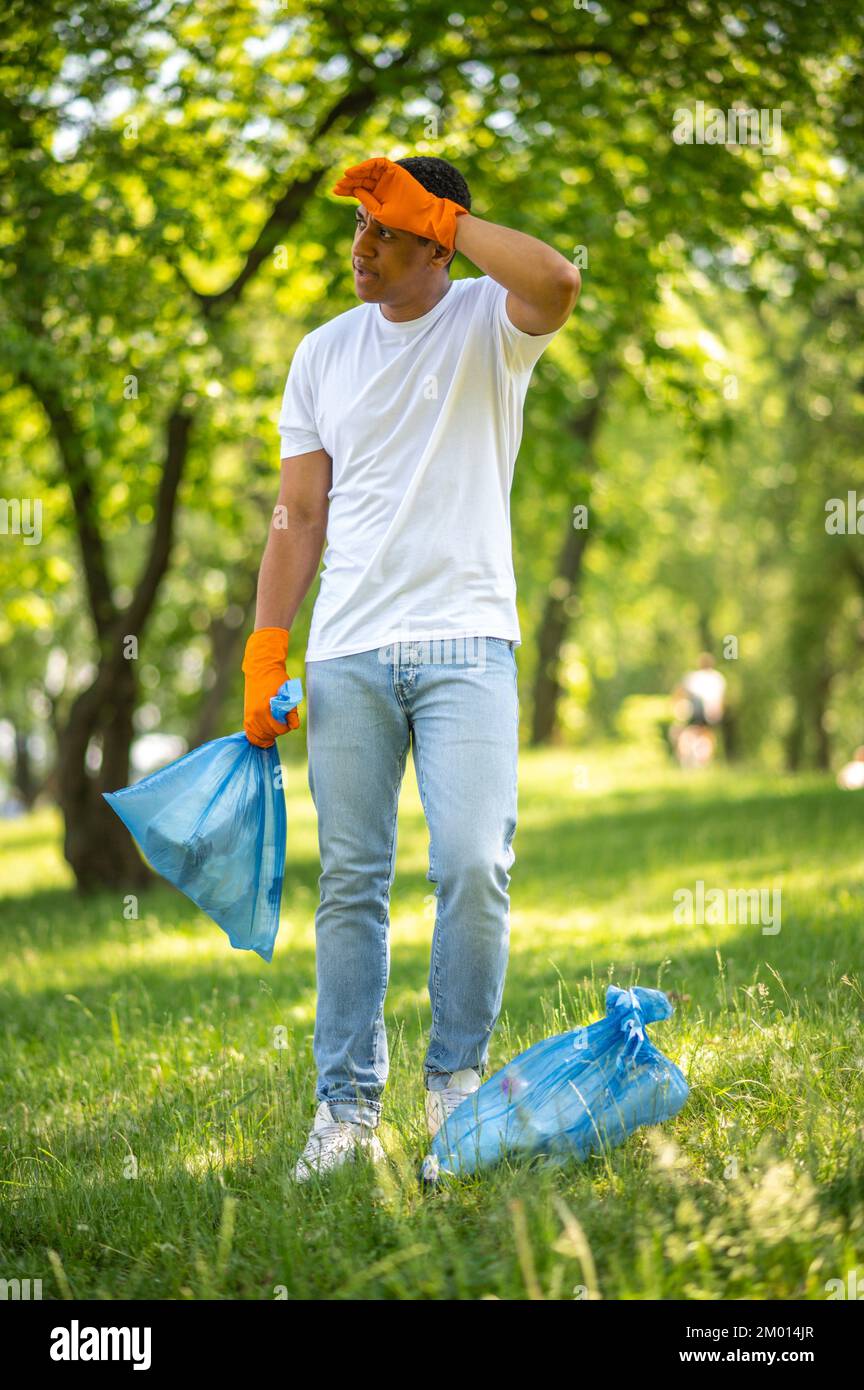 Short break. Dark-skinned guy with garbage bags standing resting ...