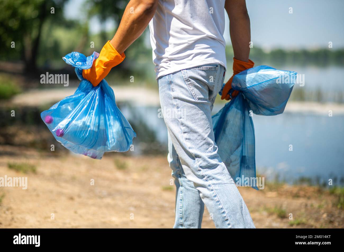 Garbage collection. Dark-skinned guy in gloves with back to camera ...