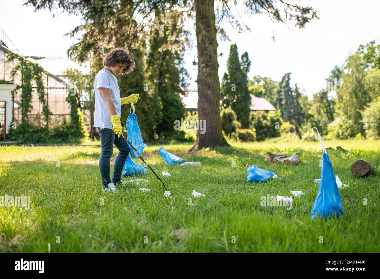 Volunteer. Cute young volunteer cleaning the park from plastic garbage ...