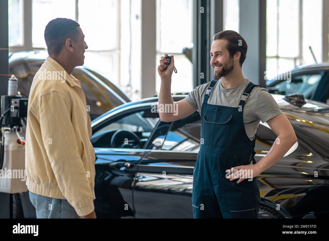 Gas station. Smiling caucasian bearded worker with car key looking ...