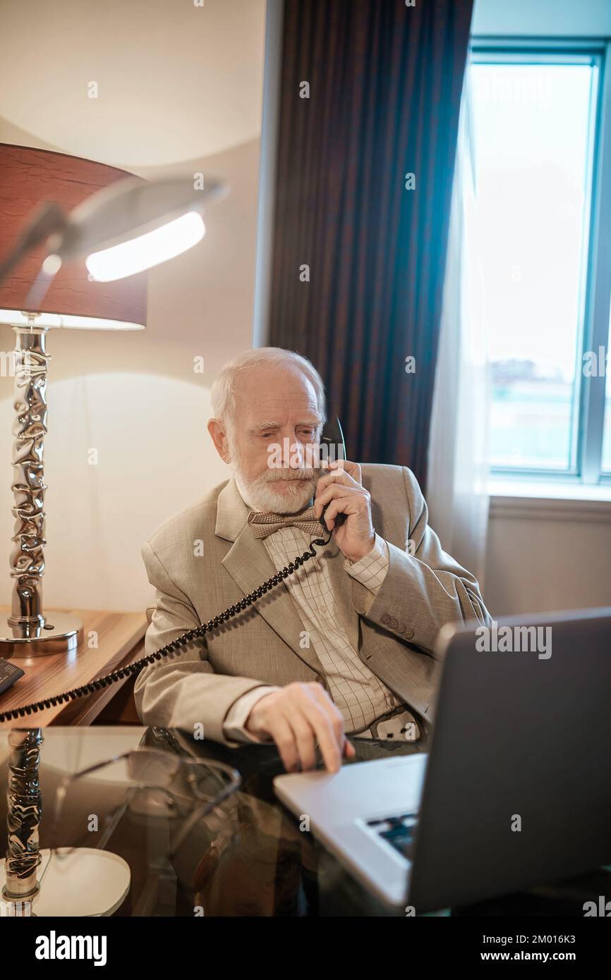 Calling room service. A gray-haired gentleman calling to the room ...