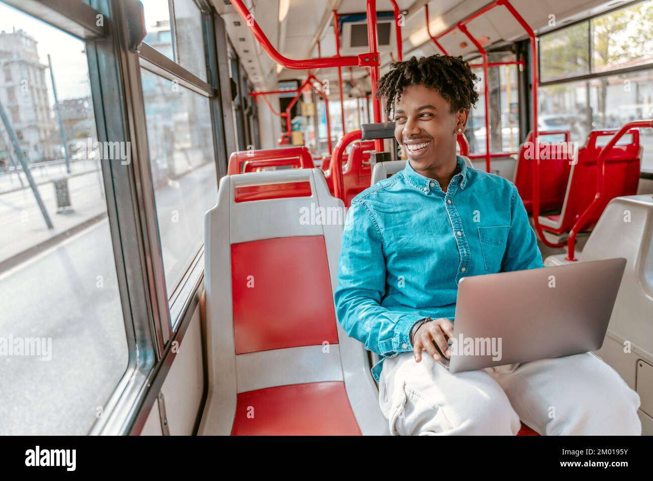 Lucky Day Happy African Guy Sitting With Open Laptop In City Bus Smiling Looking Out Window On