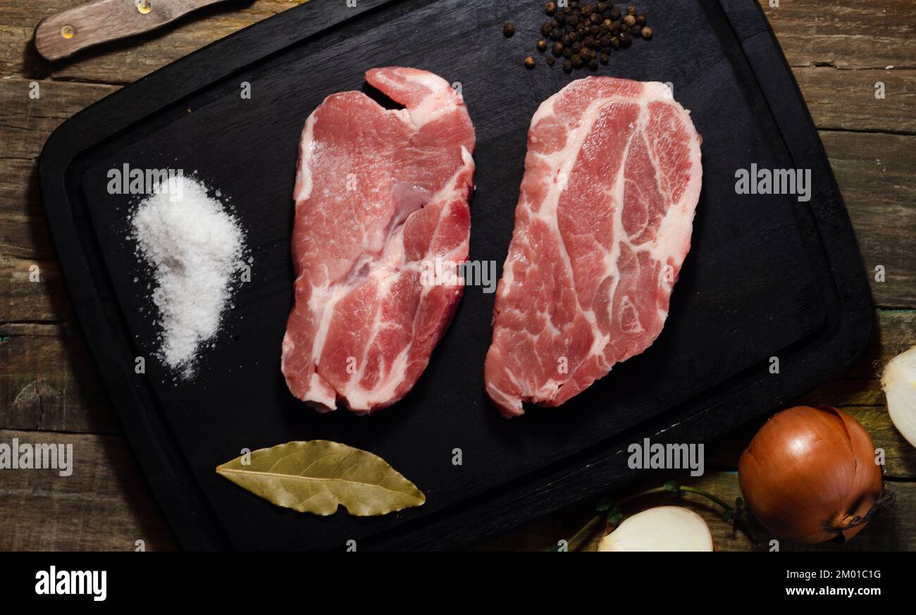 Food concept Organic Fresh pork chop on black slate stone board with ...