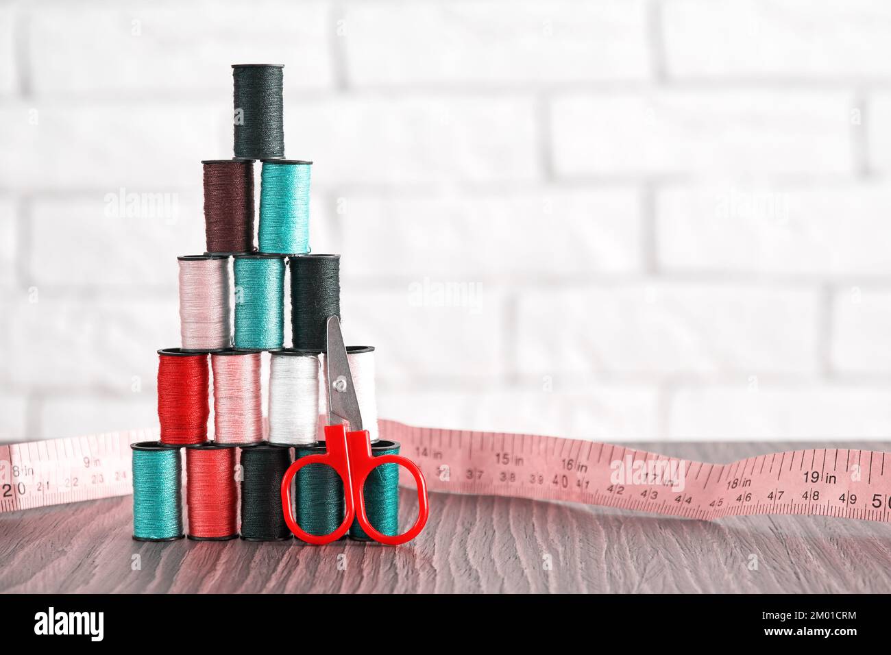 Pastel colored tailor threads stacked in pyramid form with scissors and ...