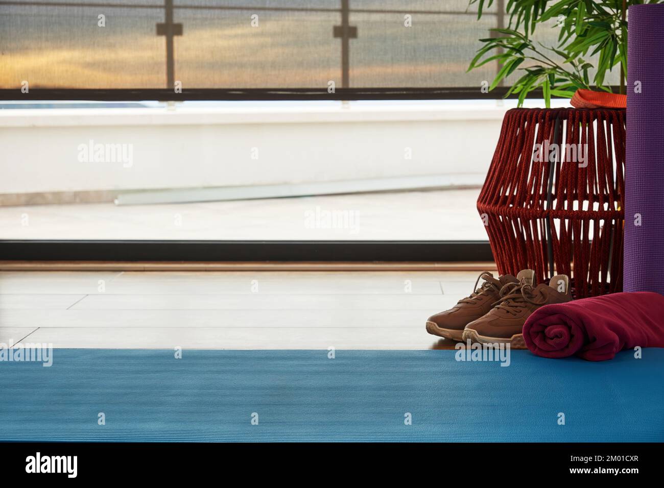 Cozy fitness room with exercise mat, towel and sneakers for yoga and ...