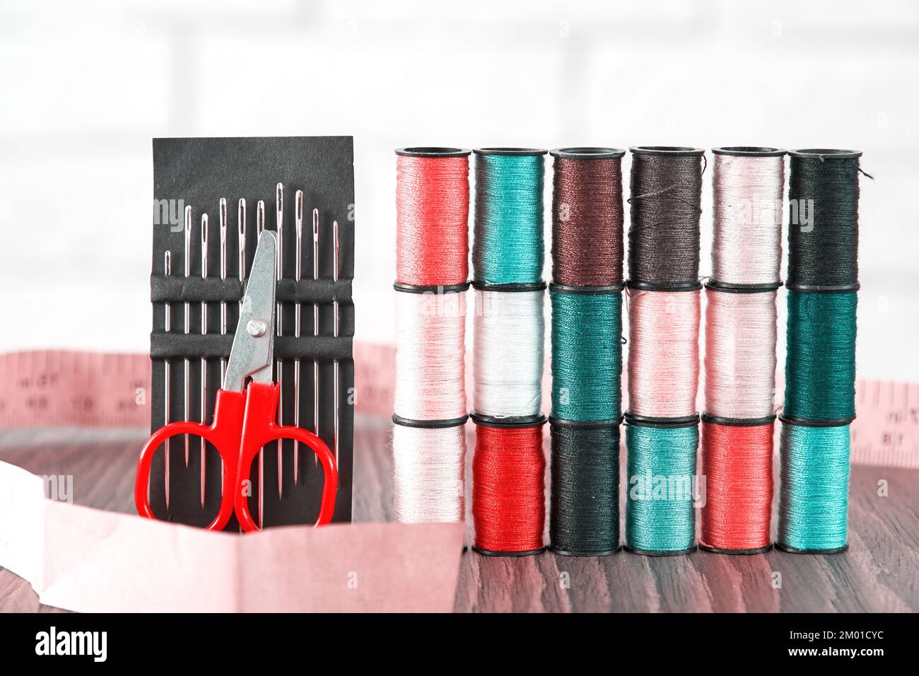 Pastel colored tailor threads with scissors, needles and measuring tape. Embroidery and sewing ...