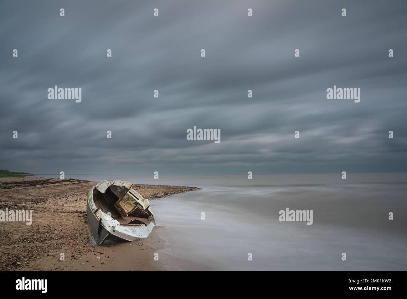 Old, damaged boat on the beach on Mersea Island in Essex. Long exposure ...
