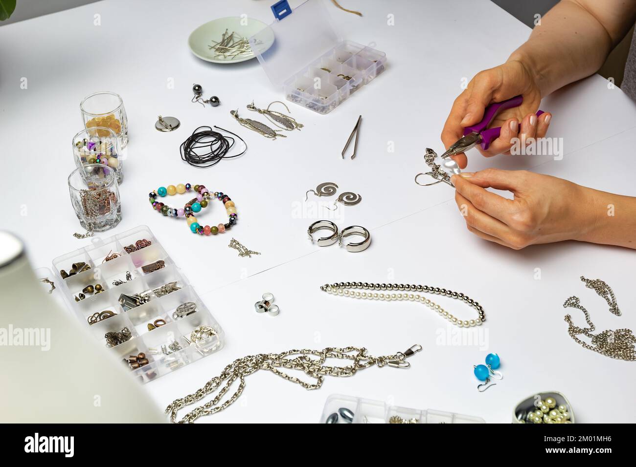 The designer makes handmade jewelry at the workplace Stock Photo - Alamy