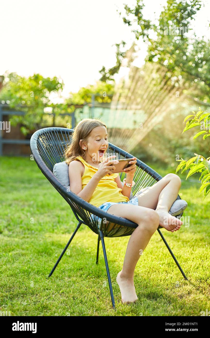 Happy kid girl playing game on mobile phone in the park outdoor, child ...