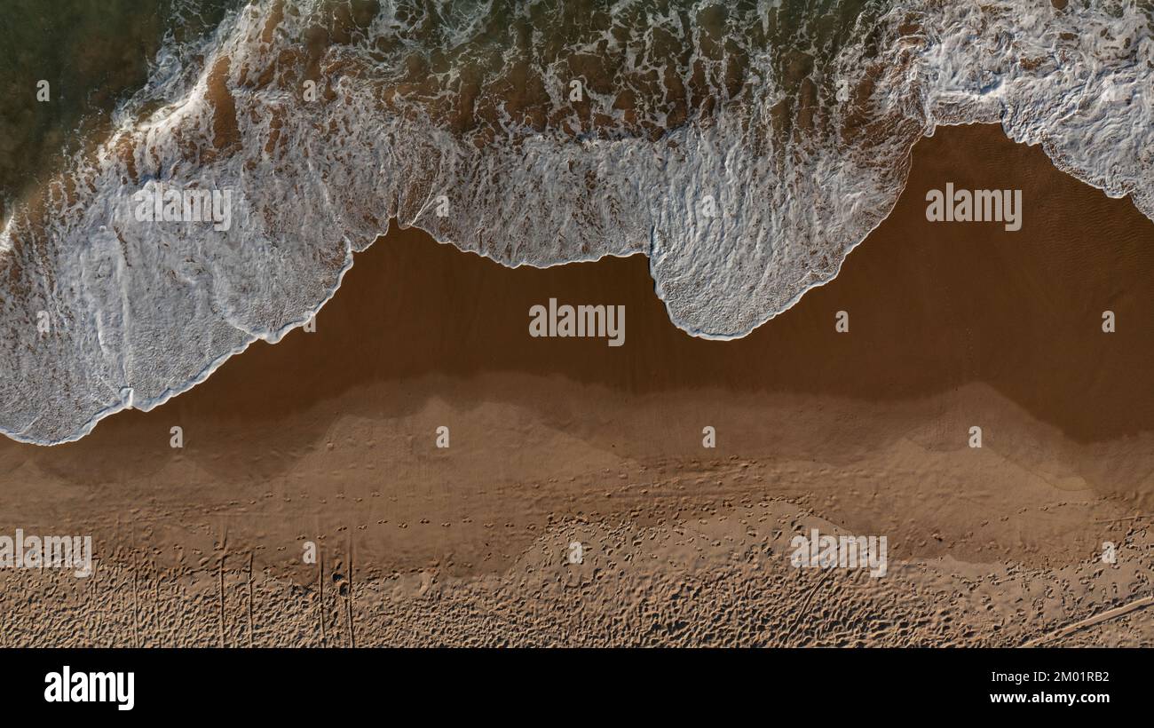 top view of wave forming foam when it hits the beach sand Stock Photo ...