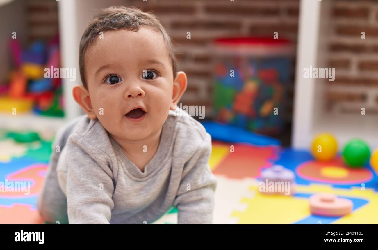 Adorable hispanic baby crawling on floor at kindergarten Stock Photo ...