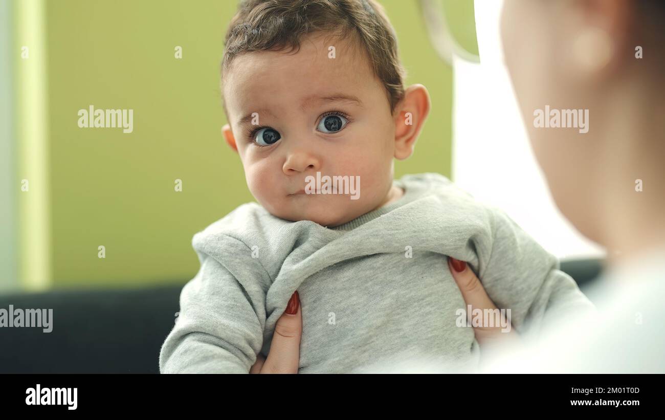 Adorable hispanic baby smiling confident relaxed on mother hands at ...