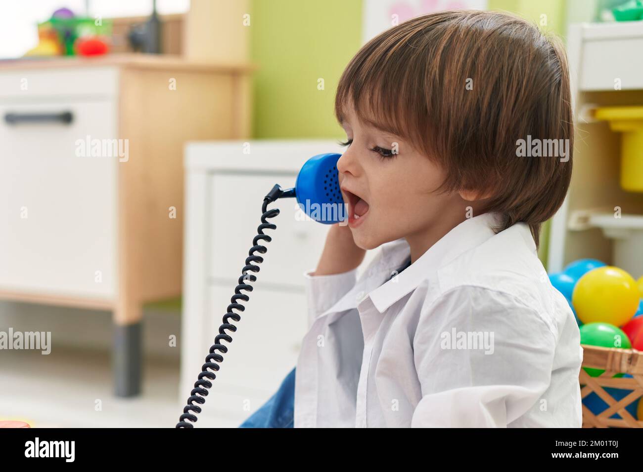 Adorable toddler playing with telephone toy sitting on floor at ...