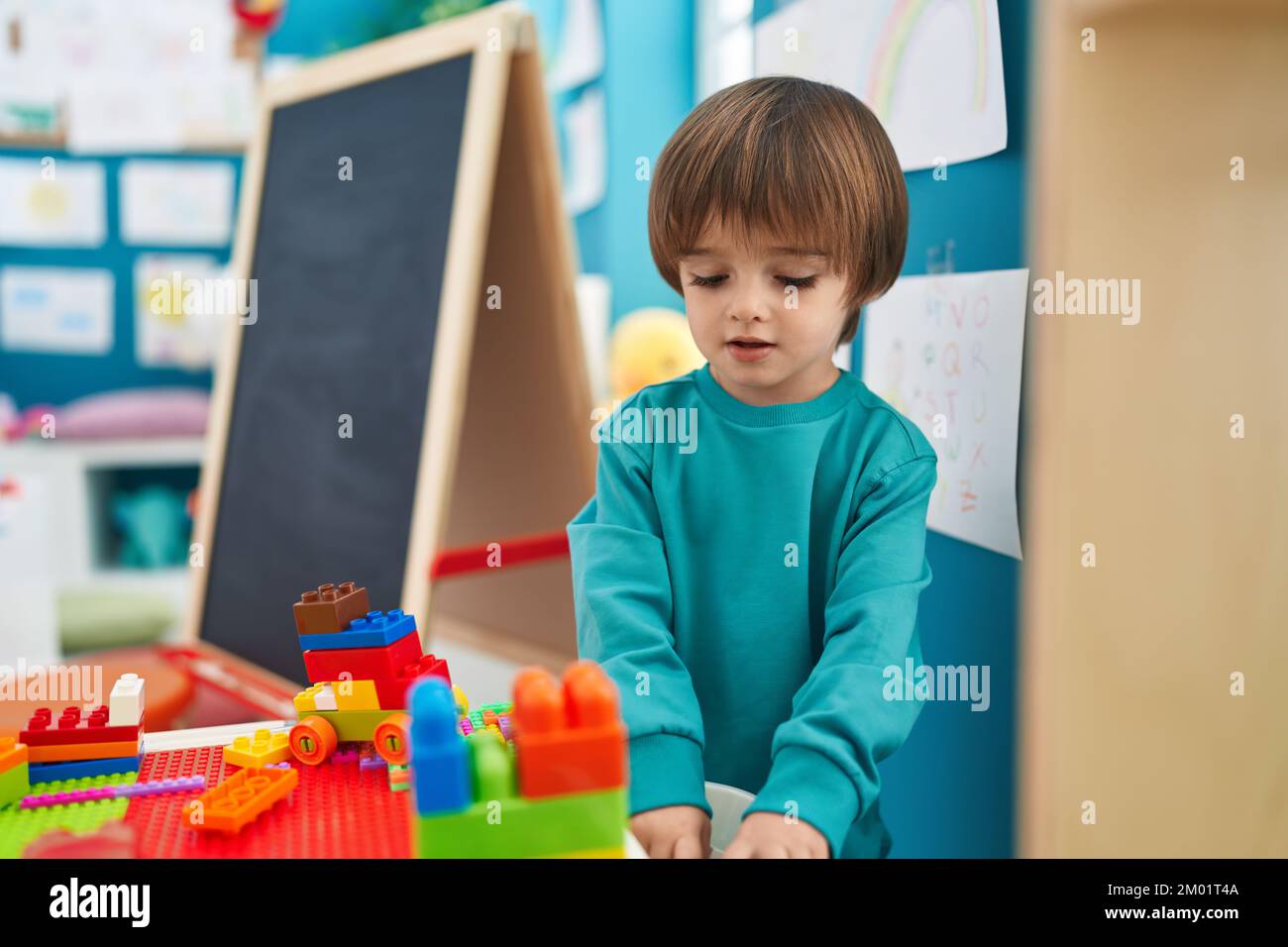 Adorable toddler playing with construction blocks standing at ...