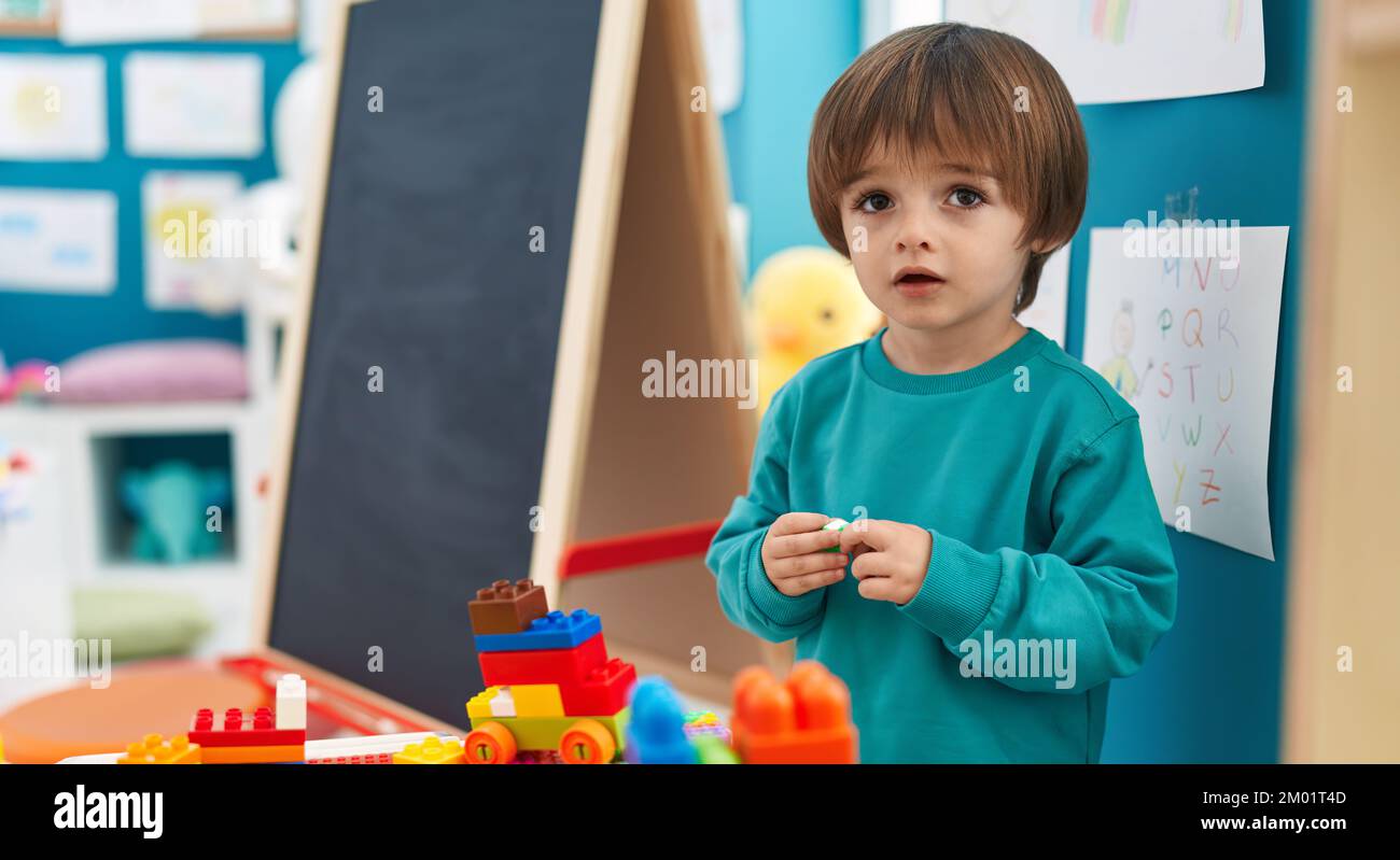 Adorable toddler playing with construction blocks standing at ...