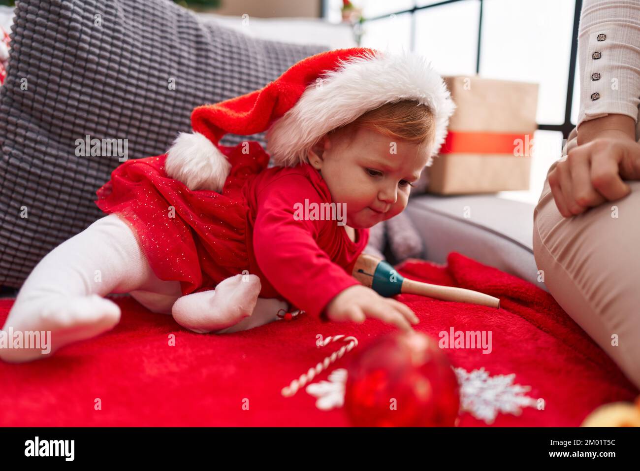 Adorable redhead toddler holding christmas decoration ball sitting on ...