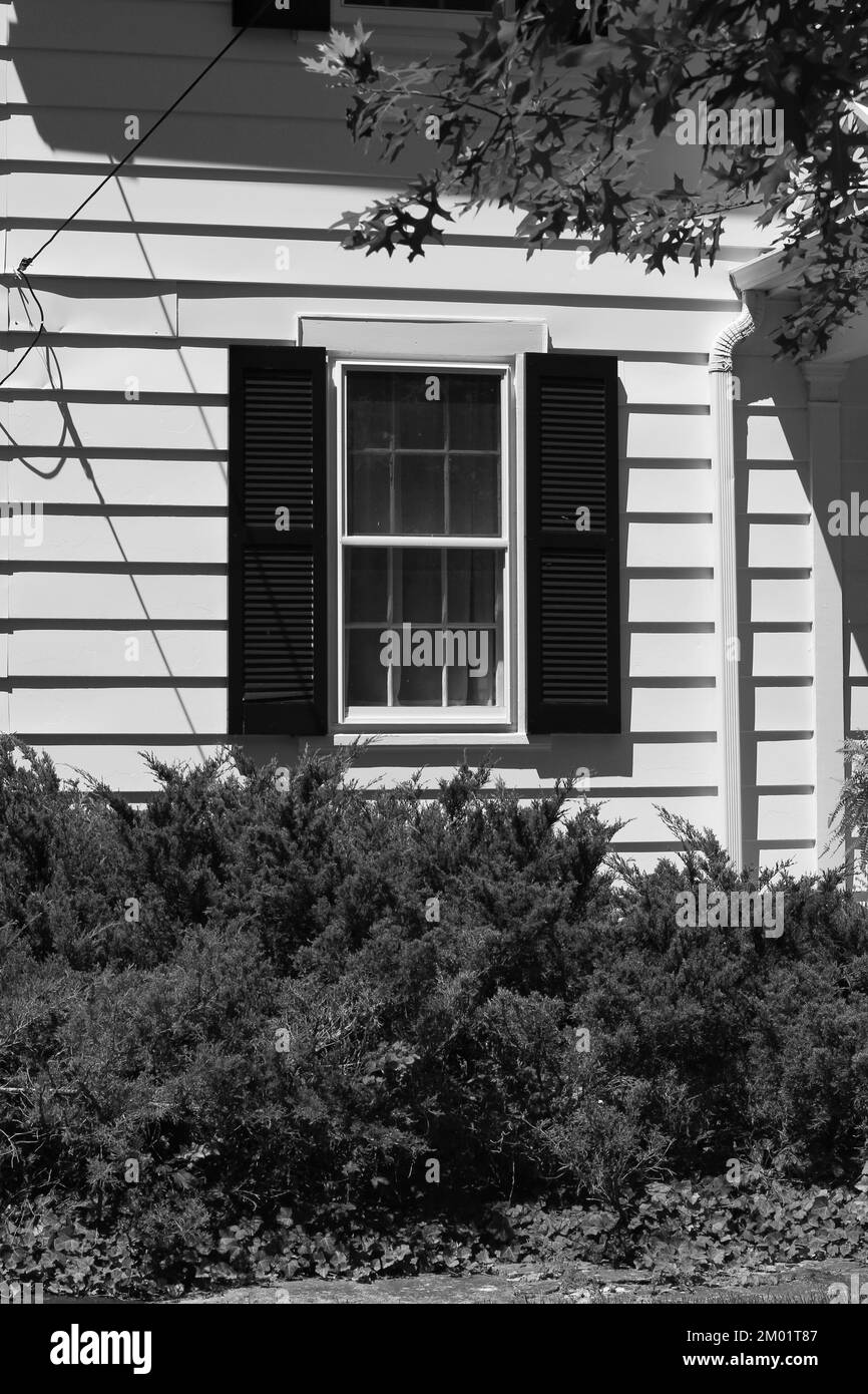 Traditional wooden cottage window on the wall of a house in a black and ...