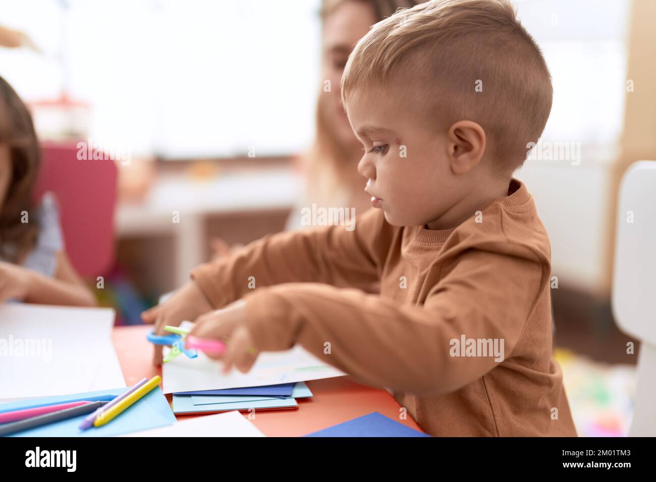 Adorable toddler student drawing on notebook sitting on table at ...